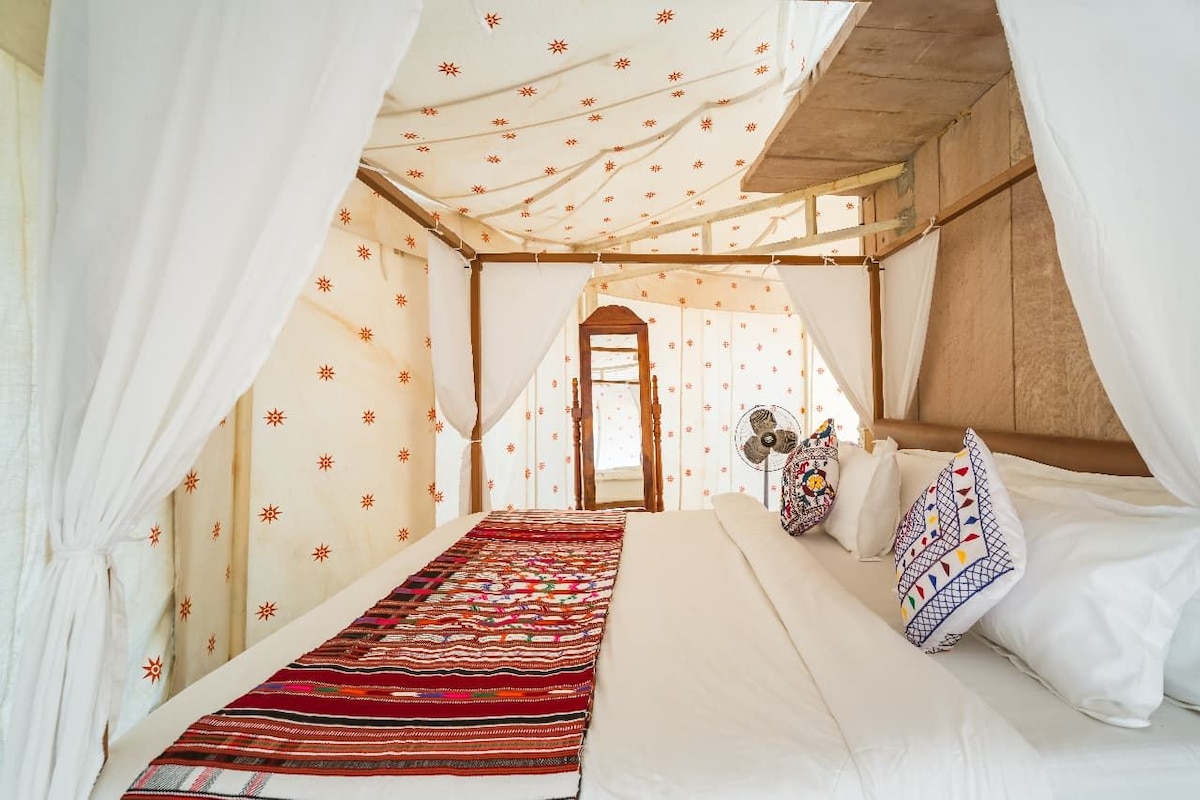 Quarto com uma cama, um tapete estampado e um ventilador.