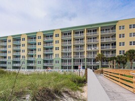 Um hotel com vários andares, varandas, um calçadão e uma área de praia arenosa.