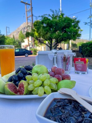 Uma mesa com um prato de frutas, um copo de suco de laranja e uma tigela de frutas secas.