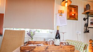 Uma mesa de madeira com uma garrafa de vinho, copos e um menu.