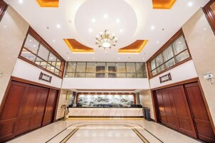 Um hall amplo com piso de mármore, um lustre imponente e uma grande janela com vista.