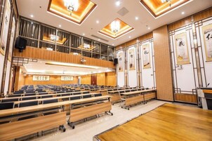 Um auditório com assentos em níveis, palco e piso de madeira.