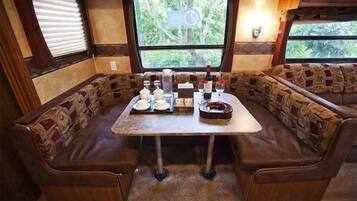 Interior acolhedor de uma motorhome, com mesa de jantar, assentos acolchoados e janela com vista.