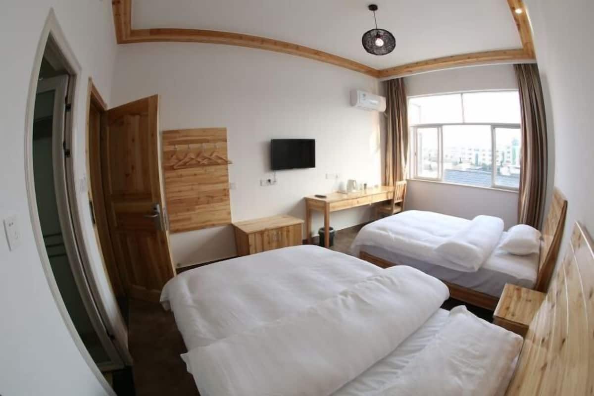 Quarto com duas camas, televisão e janela com vista para a cidade.
