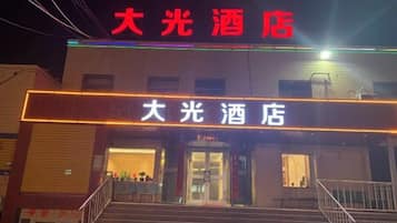 Entrada de hotel com placa em caracteres chineses, escadaria e corrimão.