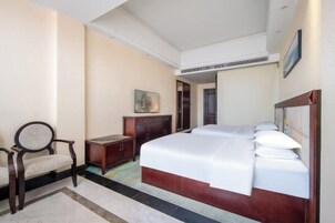 Quarto de hotel com cama, poltrona, escrivaninha e guarda-roupa.
