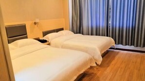 Quarto de hotel com duas camas, soalho de madeira, janela com cortinas e mesa de cabeceira.