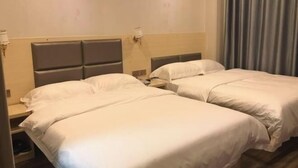 Quarto de hotel com duas camas de solteiro, uma mesa de cabeceira, uma luminária e uma cortina.