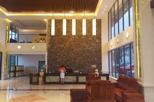 Um hall com parede de pedra, balcão de recepção em madeira e área de estar.