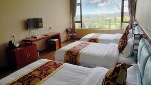Quarto de hotel com duas camas, uma escrivaninha, televisão e uma janela grande com vista.