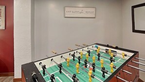 Uma mesa de futebol de mesa em um quarto com uma placa na parede que diz 'COMER DORMIR DORMIR REPETIR'.
