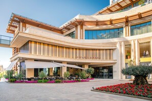 Um hotel moderno com fachada curva, área de estar ao ar livre e um jardim paisagístico.
