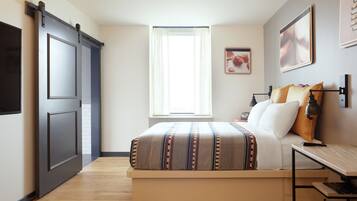 Quarto moderno com cama, mesa de cabeceira, abajur e janela com cortinas.