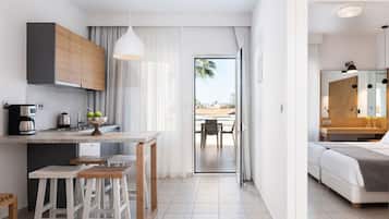 Quarto de hotel moderno com cozinha compacta, área de refeições e quarto.