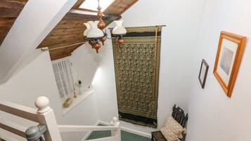 Uma escada com corrimão branco, teto de madeira e luminária pendente.