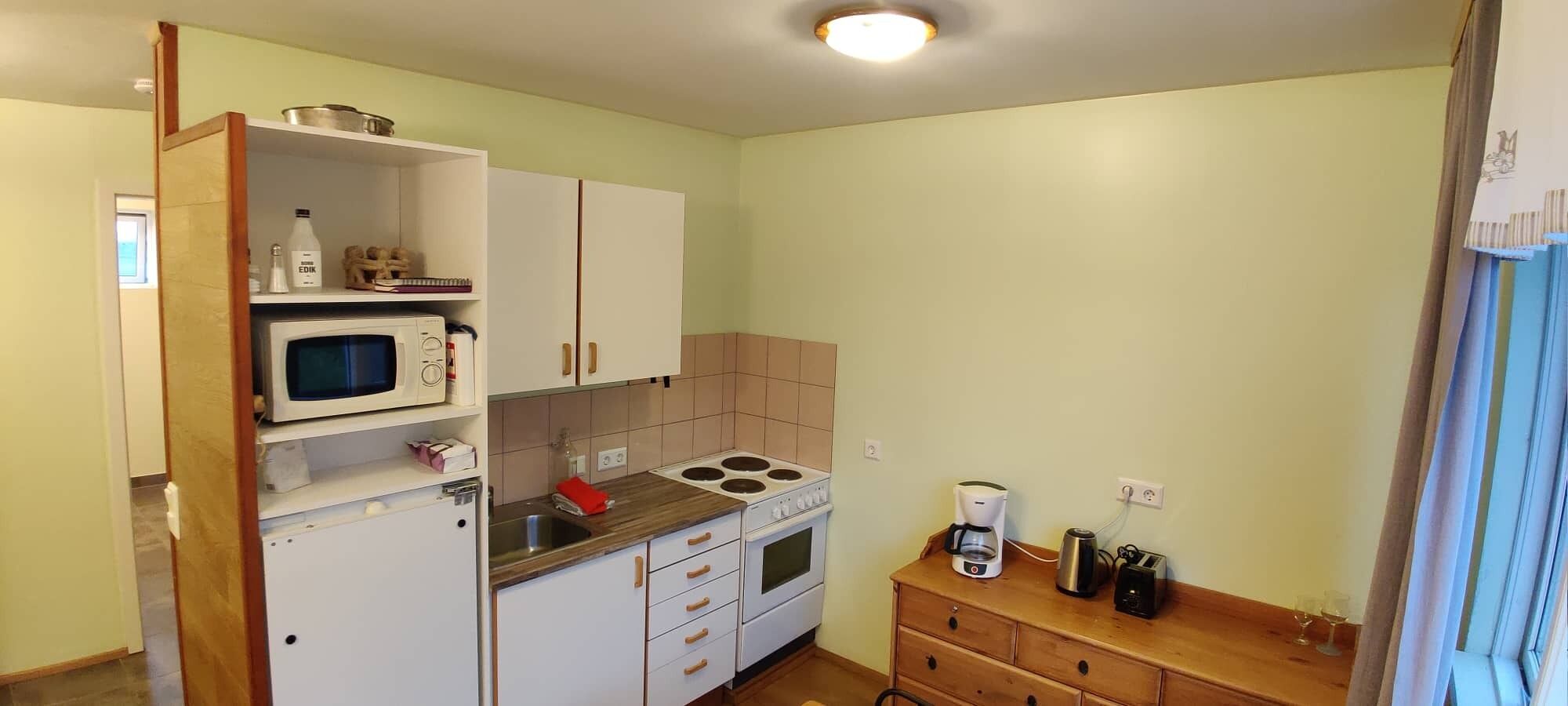 Uma cozinha compacta com micro-ondas, fogão e máquina de café.