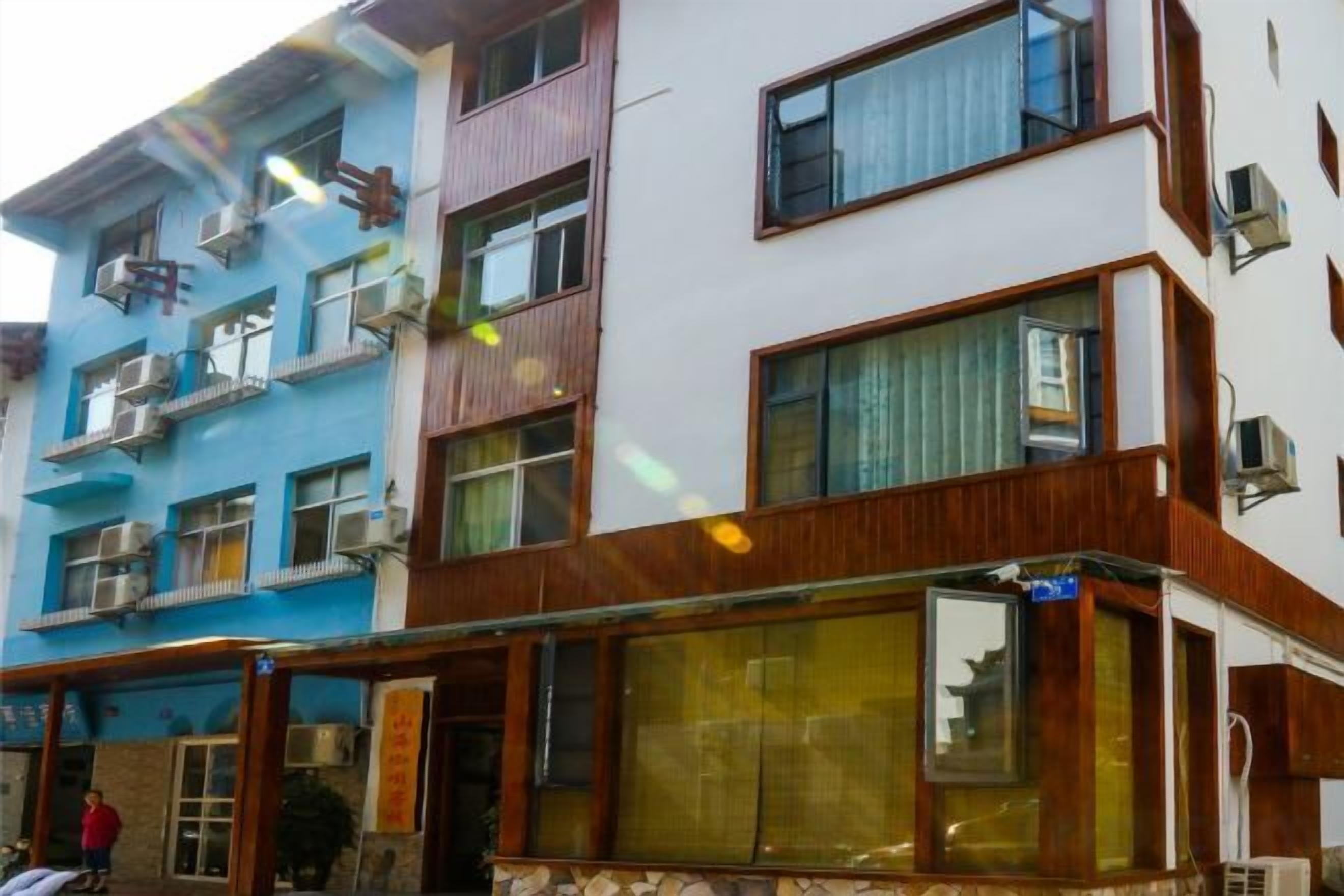 Um edifício com várias andares, varandas, janelas amplas e aparelhos de ar condicionado.