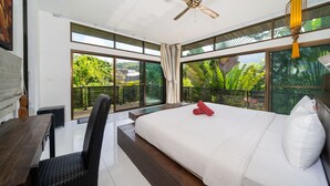 Quarto de hotel moderno com uma cama grande, uma mesa e uma cadeira. Possui uma varanda com vista para áreas verdes.