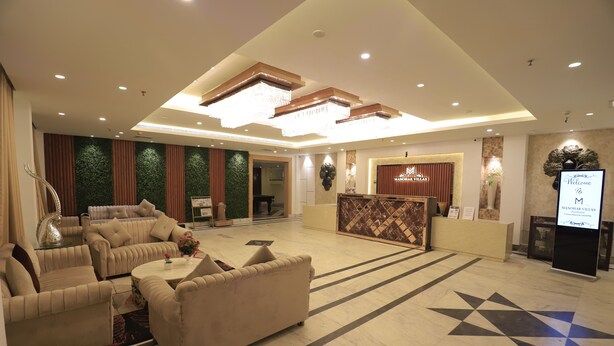 Um hall amplo com uma mesa de recepção, assentos confortáveis e um painel decorativo.