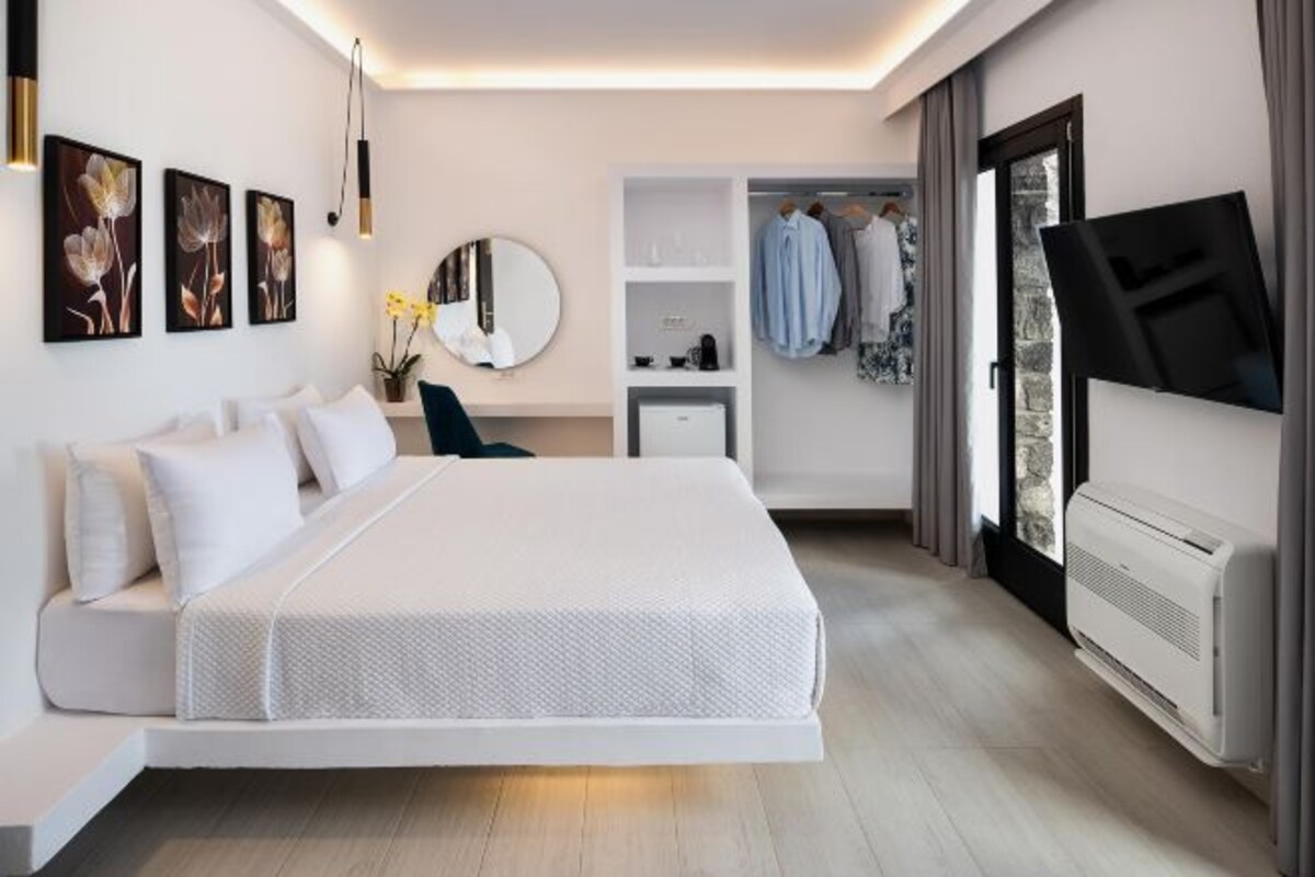 Quarto moderno com cama, mesa de cabeceira, guarda-roupa e televisão.