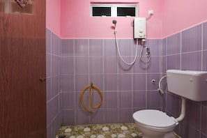 Um banheiro com parede rosa, janela, vaso sanitário e chuveiro.
