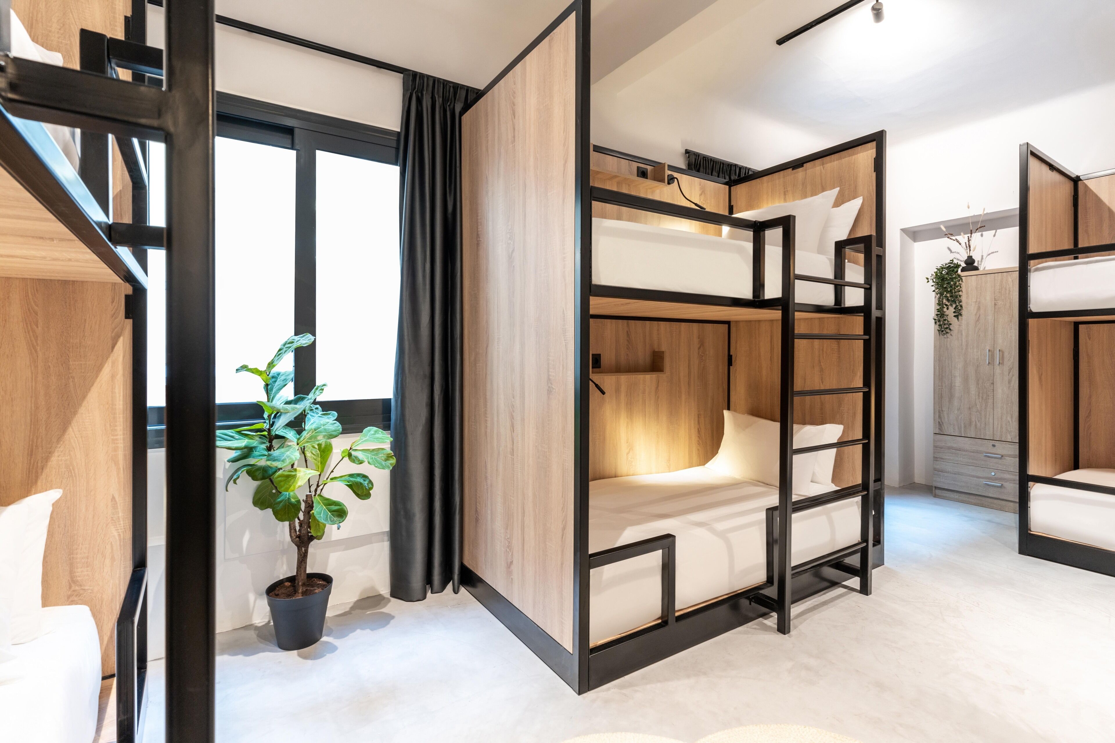 Quarto moderno e compacto com beliches, uma planta em vaso e uma escada.