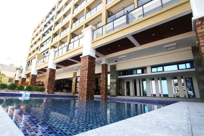 Hotel com vários andares e piscina em frente.