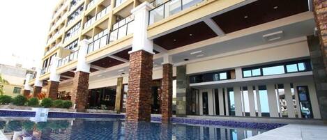 Hotel com vários andares e piscina em frente.