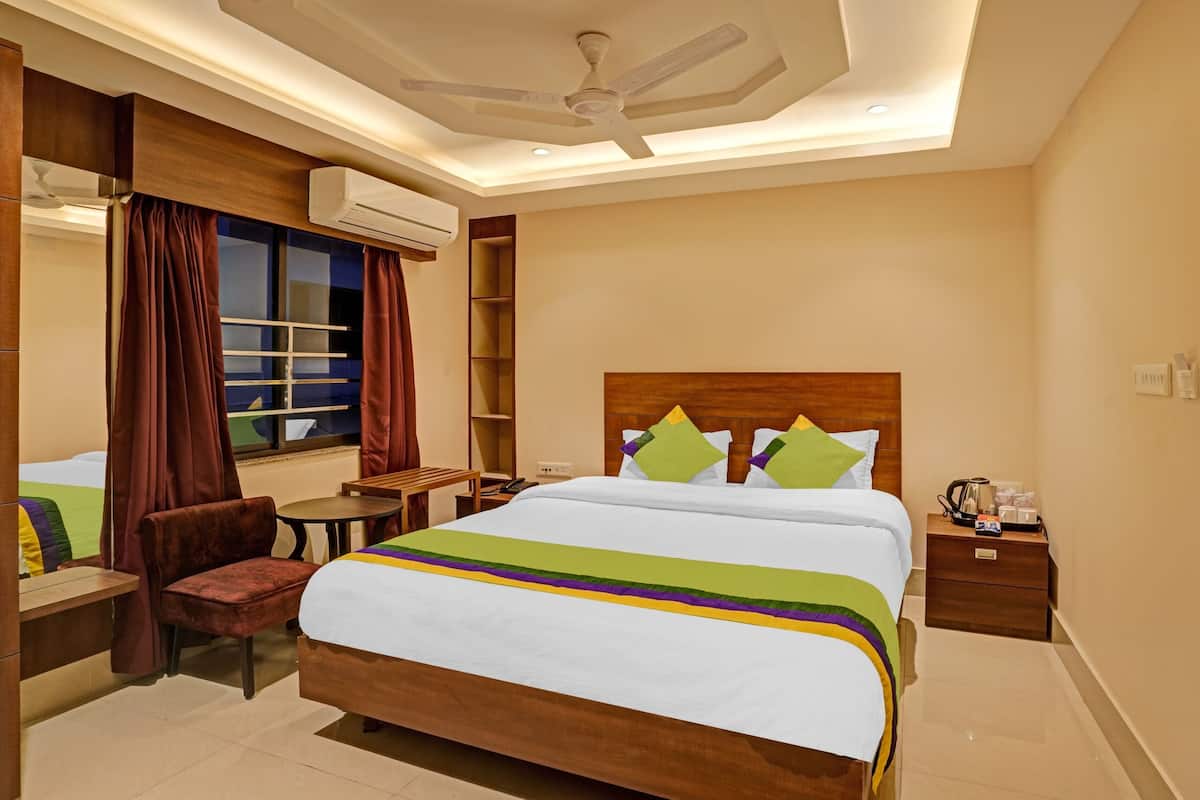 Quarto de hotel com uma cama grande, uma mesa, uma cadeira, um guarda-roupa e um ventilador de teto.