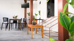 Uma área de estar ao ar livre aconchegante, com uma mesa de madeira, cadeiras e uma rede.
