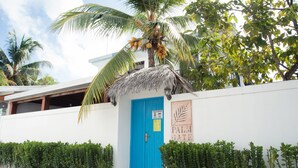 Um edifício com porta azul, uma palmeira e uma placa com a inscrição 