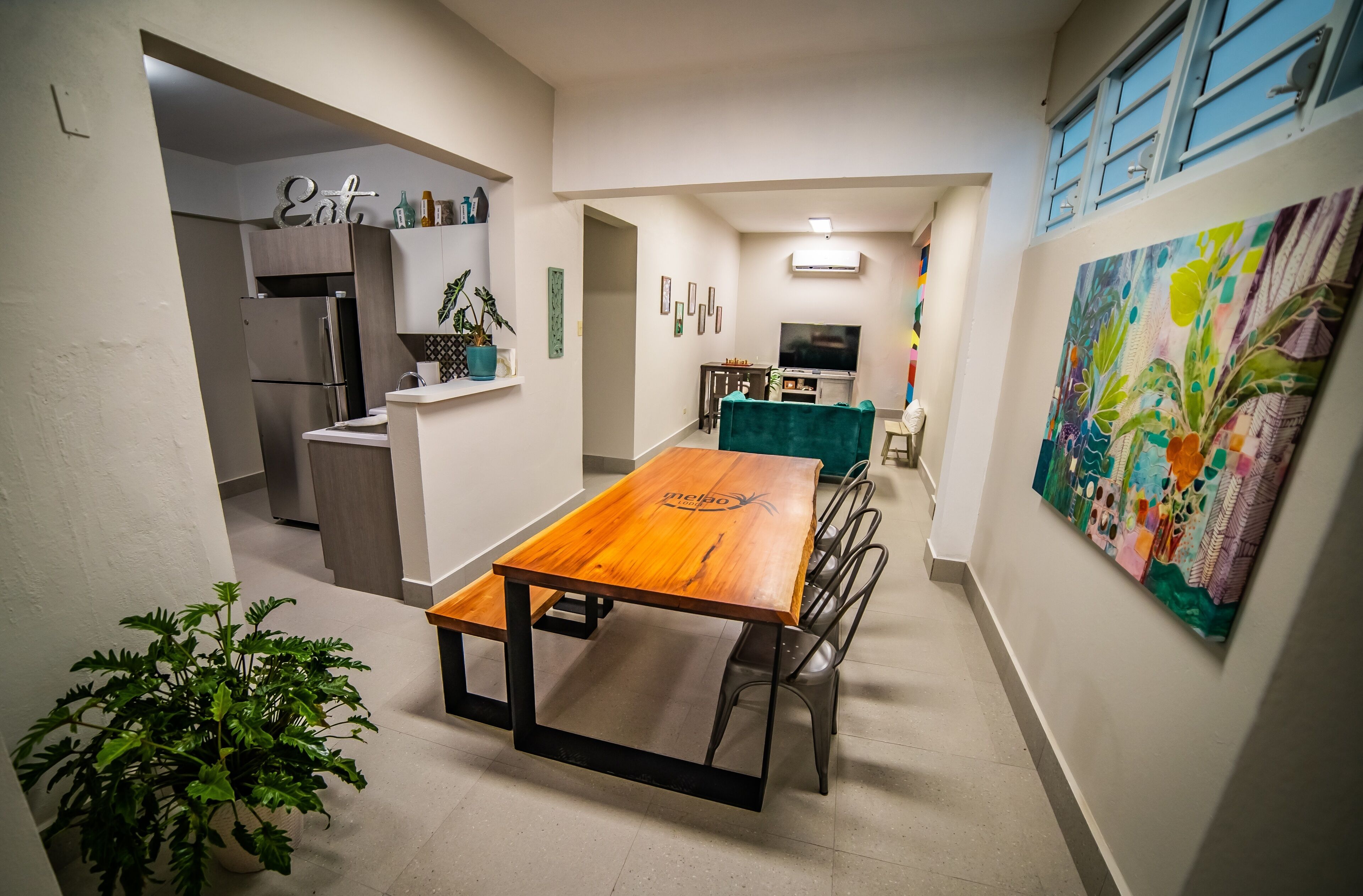 Espaço compacto com cozinha, área de refeições e televisão.