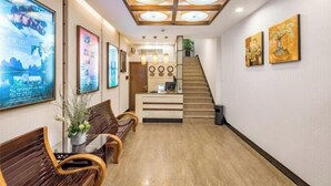 Uma área de recepção com bancos de madeira, balcão de atendimento e uma escada.