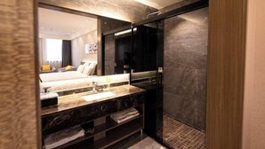 Uma casa de banho moderna com lavatório de mármore, um espelho grande e uma área de duche separada.