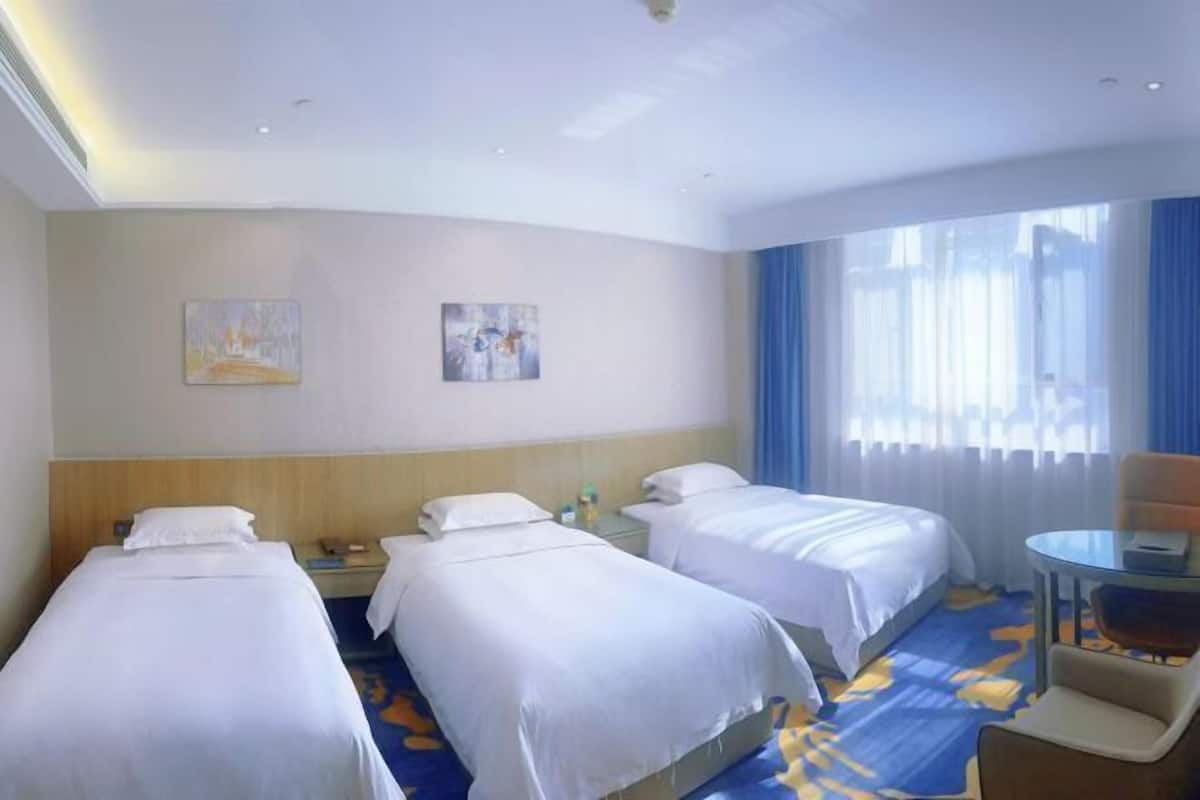 Quarto de hotel com duas camas, uma mesinha e uma cadeira.