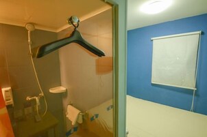 Uma casa de banho com chuveiro, sanita e janela com estore.