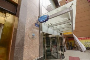 Entrada de hotel com porta giratória, placa Bestway Express e número de quarto visível 37-9.