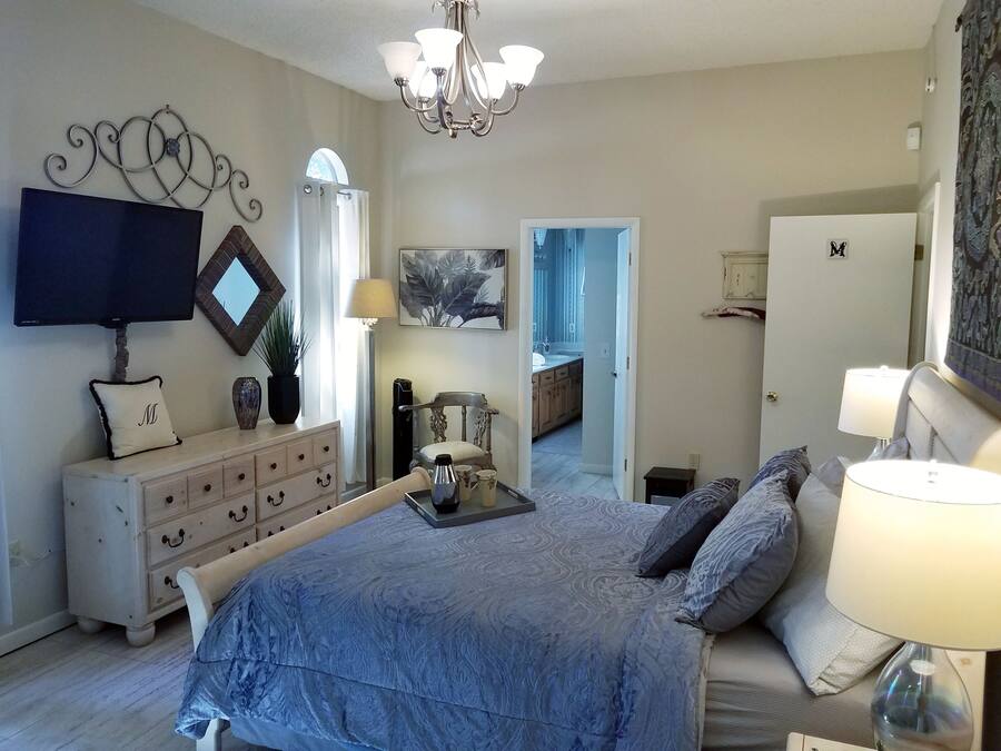 Quarto com uma cama grande, penteadeira, televisão e lustre.
