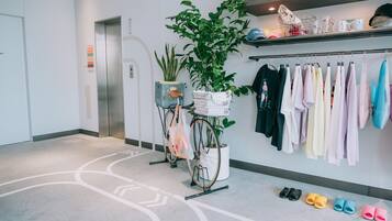 Decoração moderna com suporte para bicicleta, um vaso de planta e um cabideiro com diversas peças de roupa.