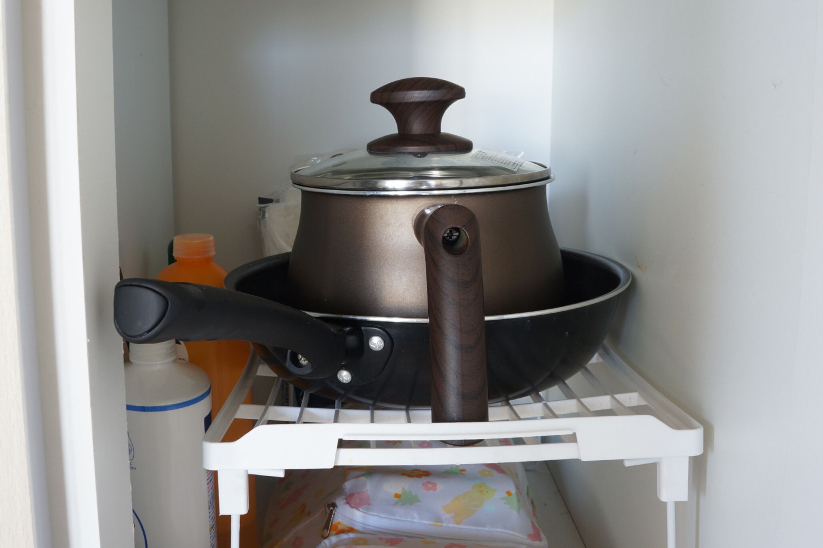 Uma cozinha com fogão, uma panela no fogão e uma garrafa de líquido laranja no balcão.