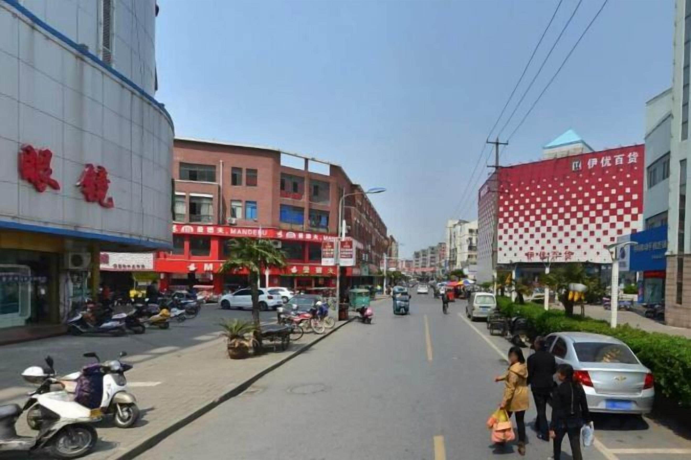Ruas com edifícios, veículos estacionados e pedestres.