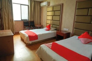 Quarto de hotel com duas camas, uma escrivaninha e uma cadeira.