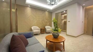 Um hall moderno com um sofá, cadeiras, uma mesa redonda de madeira e um lustre.