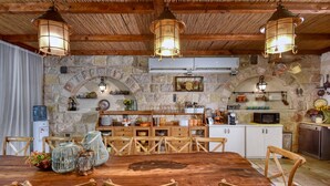 Uma área de jantar rústica com uma grande mesa de madeira, cadeiras de madeira e lanternas penduradas.