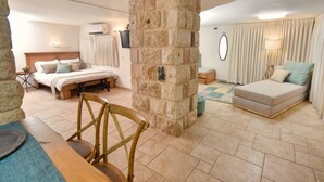 Quarto de hotel com um pilar de pedra, cama, sofá e área de jantar com mesa e cadeiras.