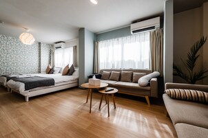Uma sala de estar moderna com um sofá, uma mesinha redonda e uma cama com um cobertor.
