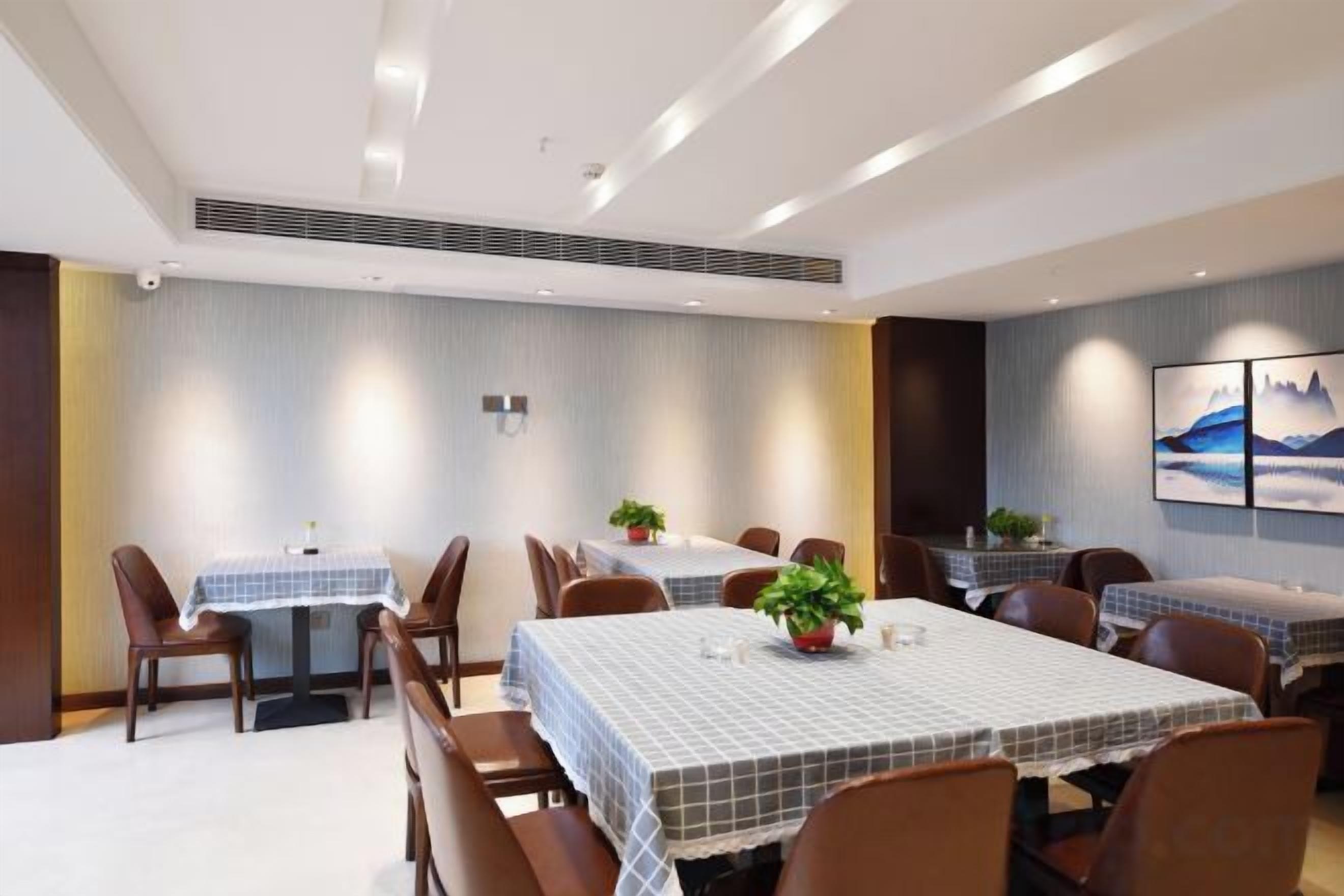 Sala de conferência com várias mesas e cadeiras, equipada com abajures e plantas em vasos.