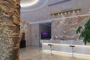 Uma área de recepção com design moderno, incluindo um balcão de atendimento, um pilar decorativo e uma tela de televisão.