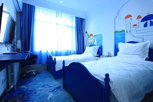Quarto de hotel com duas camas, uma escrivaninha, uma cadeira, uma televisão e uma janela com cortinas.