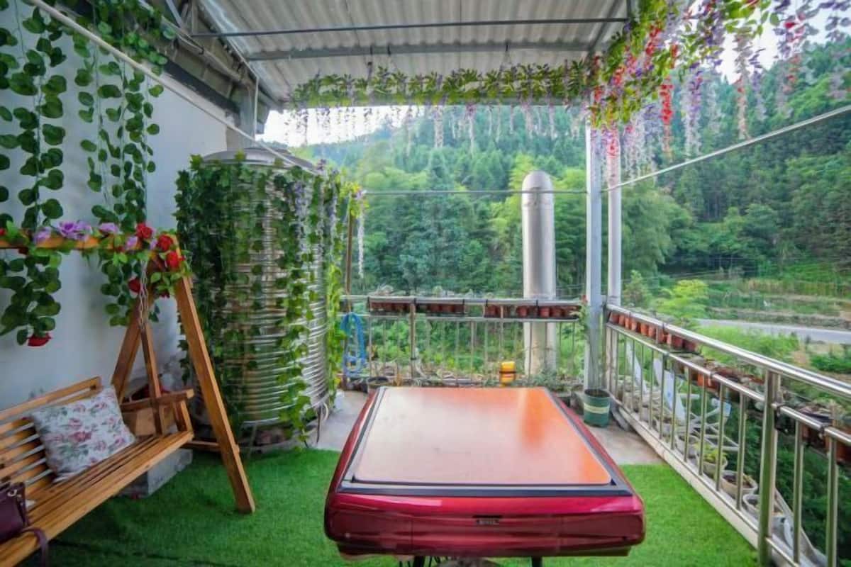Uma varanda com vista para uma floresta, uma mesa e um banco.